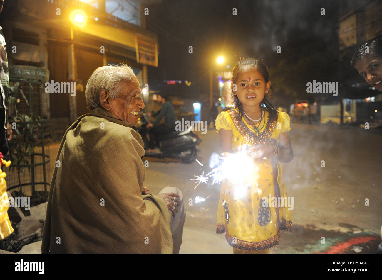 A festively dressed Indian gil holds a sparkler on the occasion of the ...