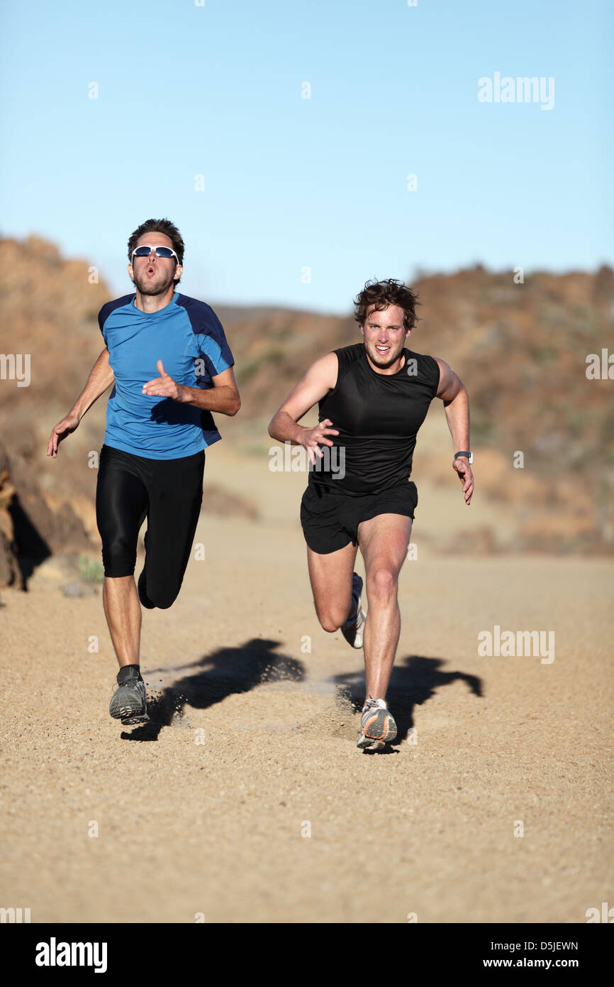Two male runner sprinting outdoor in extreme desert nature landscape ...