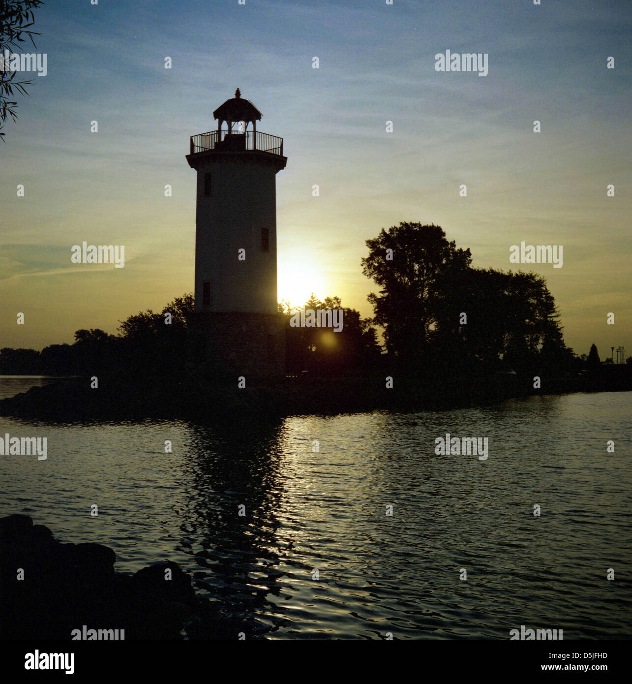 Lighthouse in silhouette with sun setting in the background Stock Photo ...