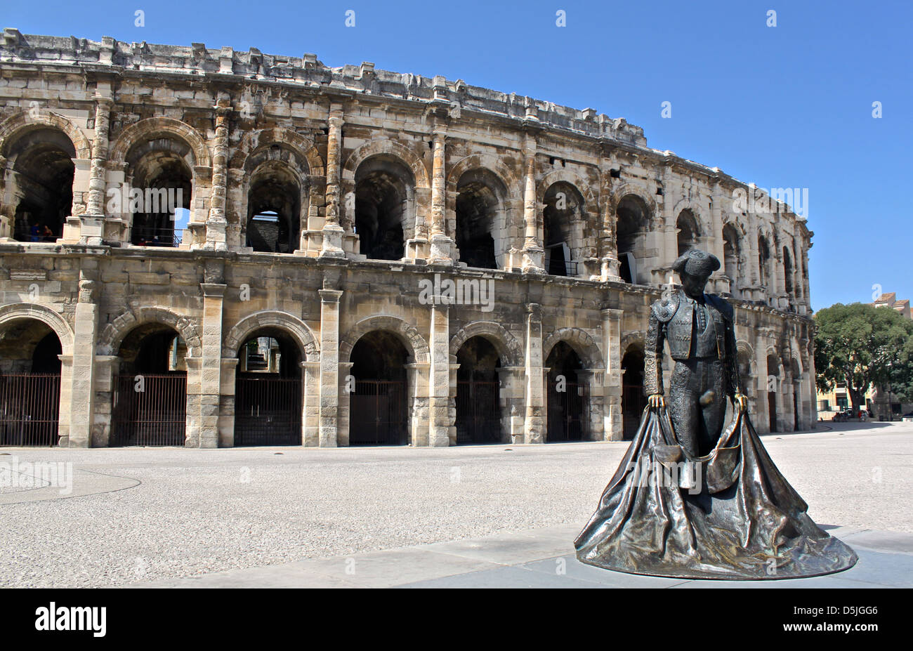 Amphitheatre at Nimes with a statue of a matador in the foreground ...