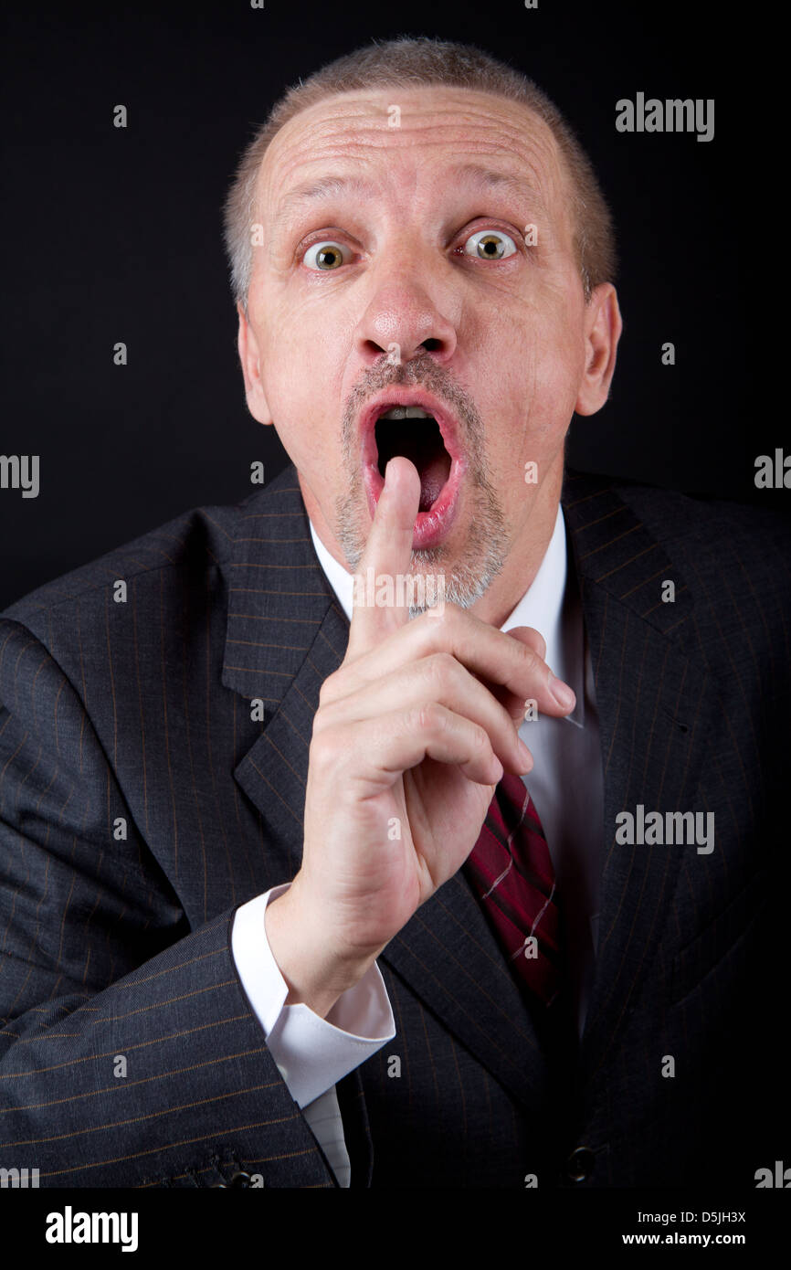 Businessman holding index finger at his mouth Stock Photo - Alamy