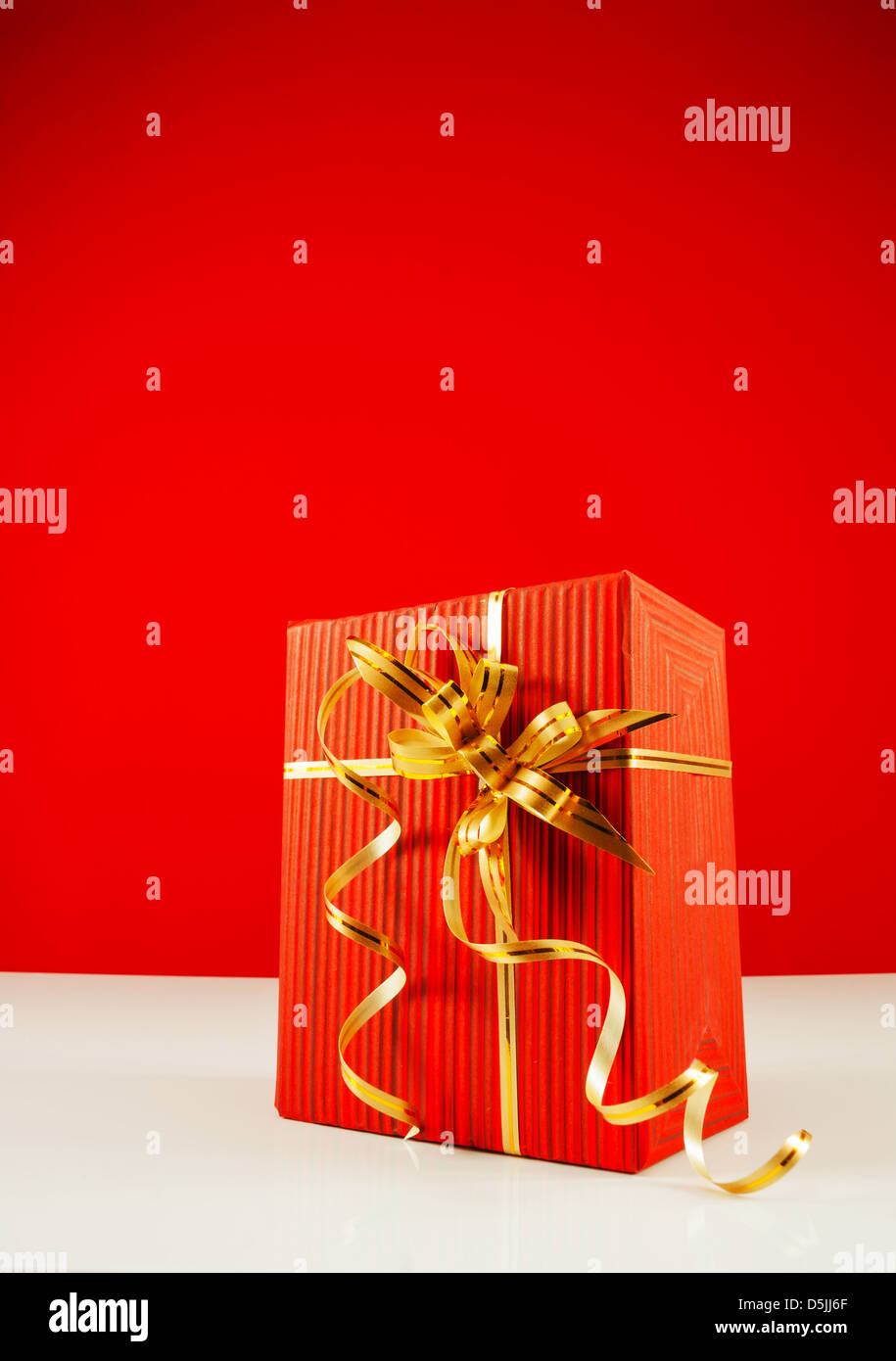 Wrapped red present box against red background Stock Photo - Alamy
