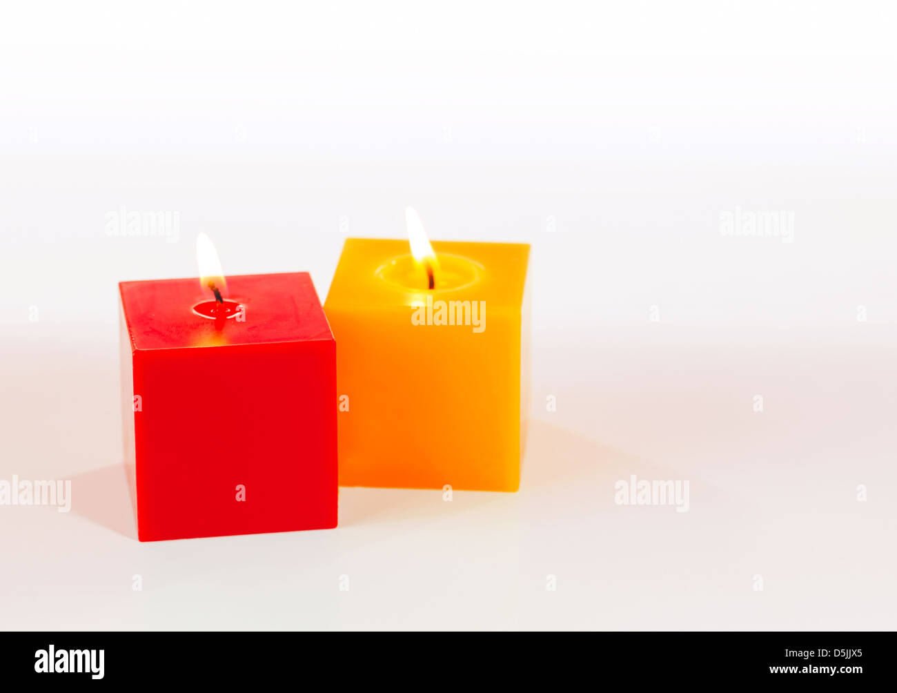 Two burning candles against white background Stock Photo - Alamy