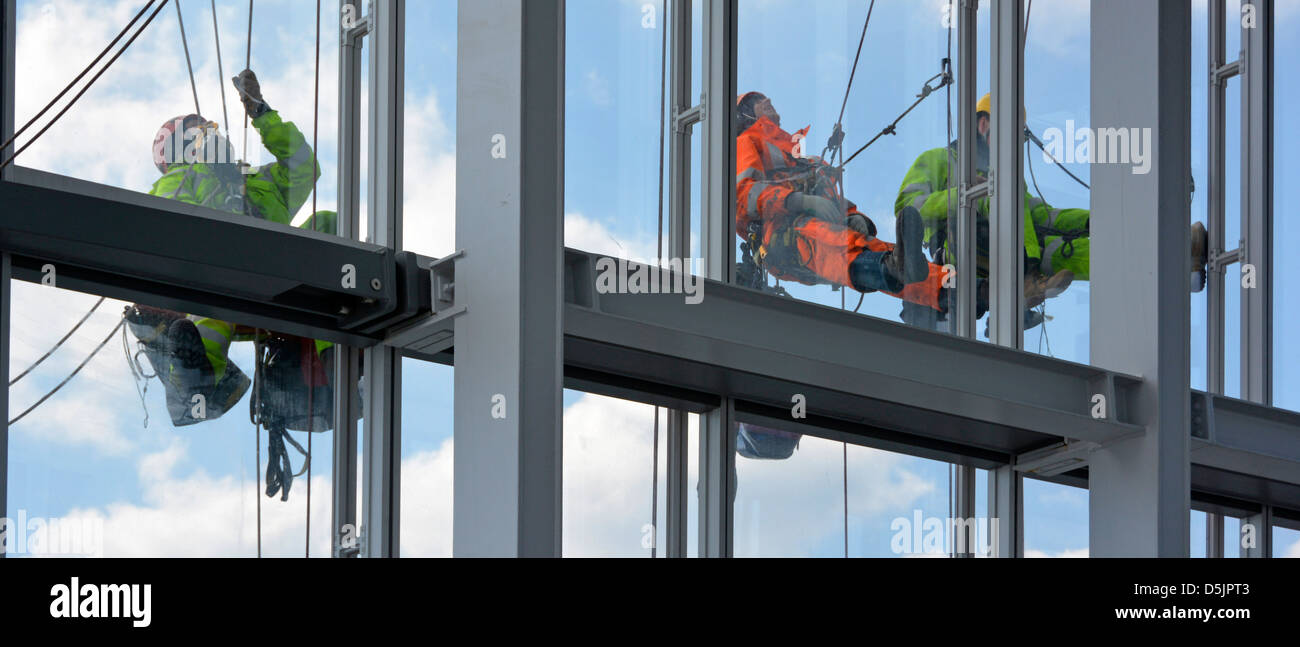 Workmen hanging on ropes on external face of a London tower block ...