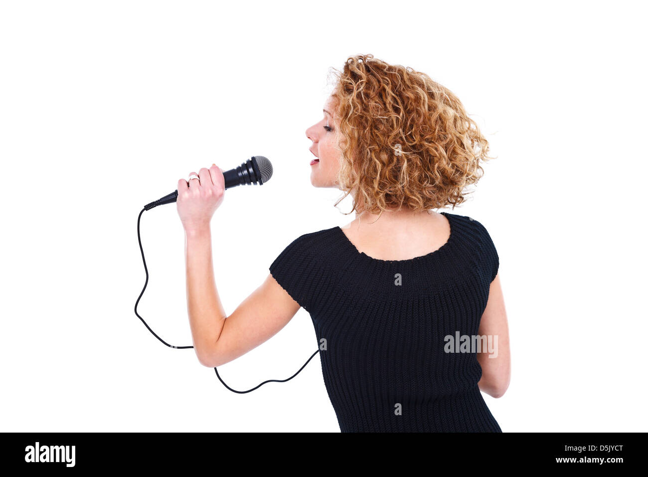 Profile of a beautiful young singer holding a microphone - studio shot ...