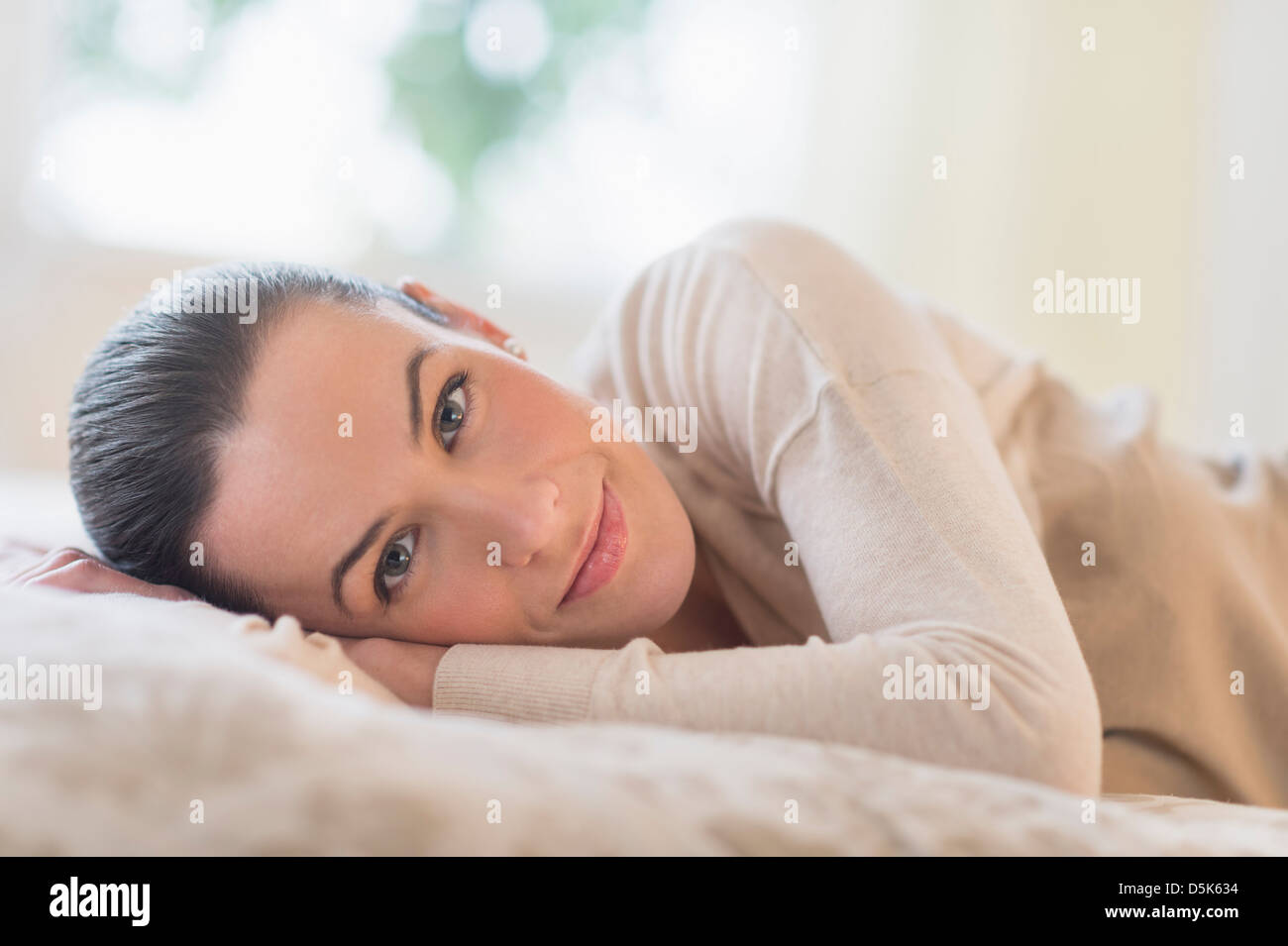 Portrait of woman lying on bed Stock Photo - Alamy