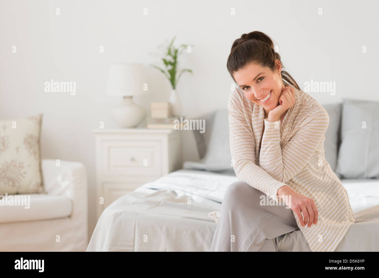 Woman sitting on bed Stock Photo - Alamy