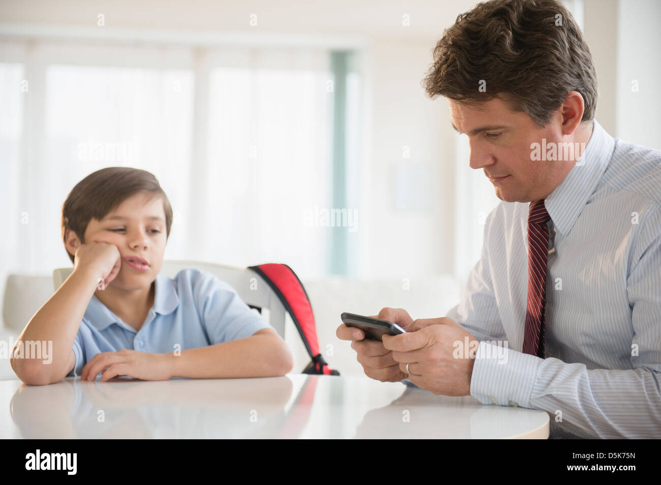 Father and son (8-9) sitting at table Stock Photo - Alamy