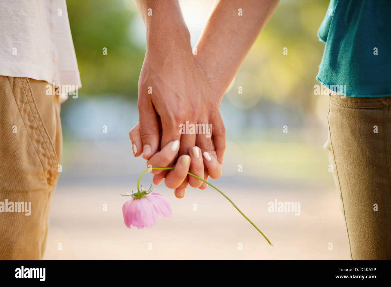 Couple holding hands and flower Stock Photo - Alamy