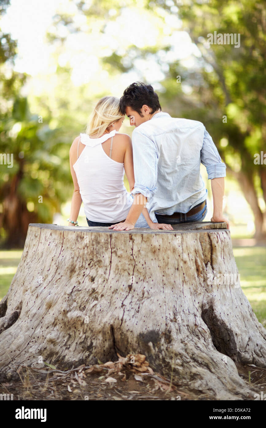 Couple sitting on tree stump Stock Photo - Alamy