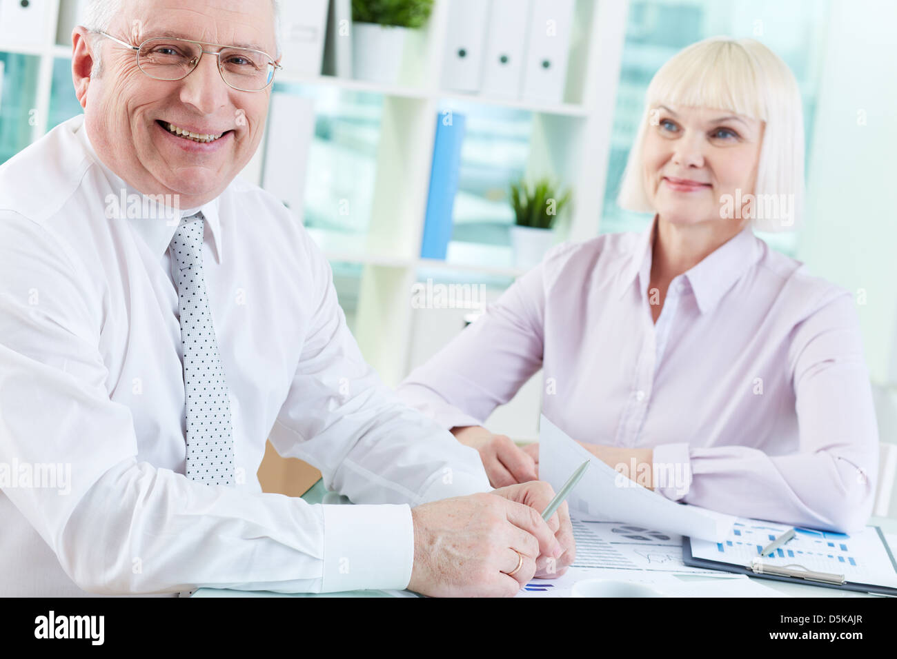 Portrait of smiling boss looking at camera at workplace with mature ...