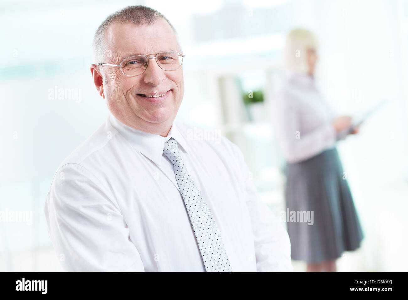 Portrait of smiling boss looking at camera with female standing on ...