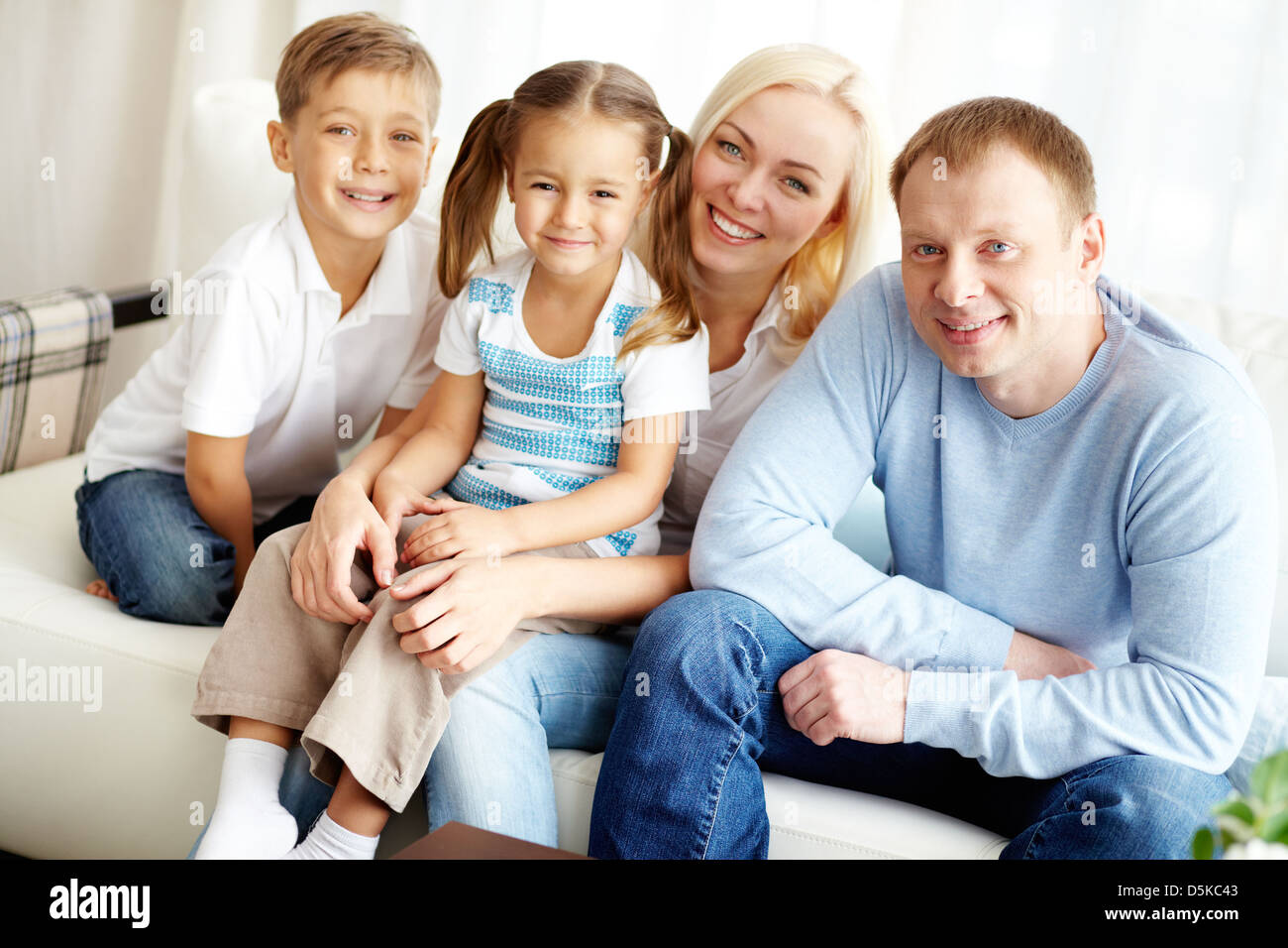 Portrait of happy family with two children sitting at home Stock Photo ...