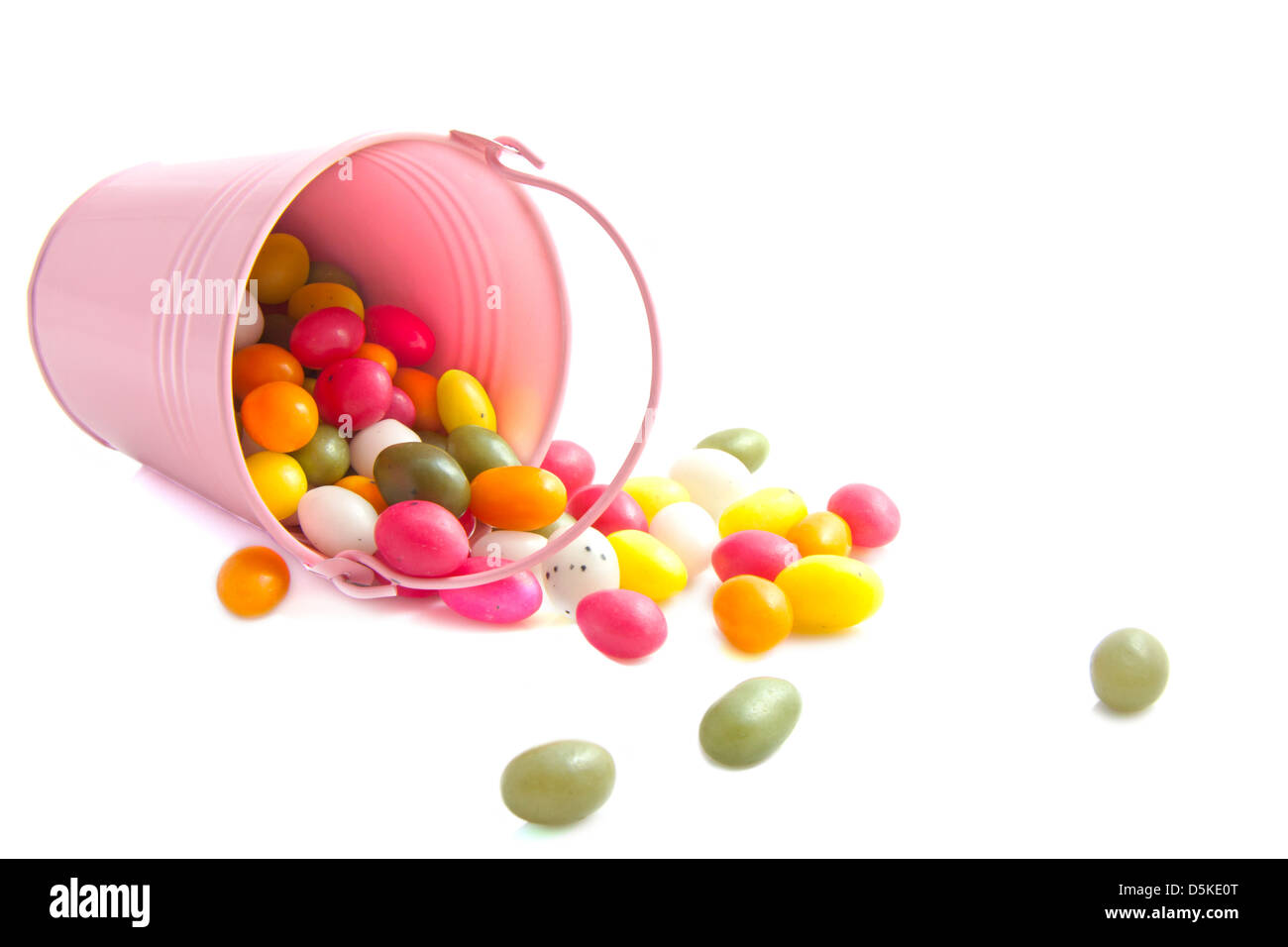 Pink bucket with colorful candy eggs over white Stock Photo - Alamy