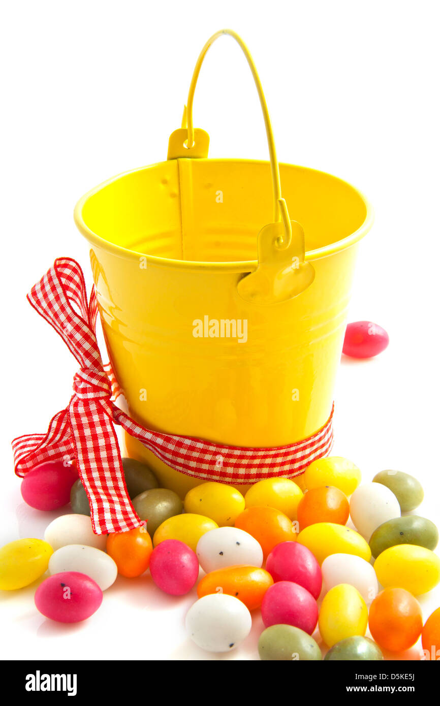 Yellow bucket with colorful candy eggs over white Stock Photo - Alamy