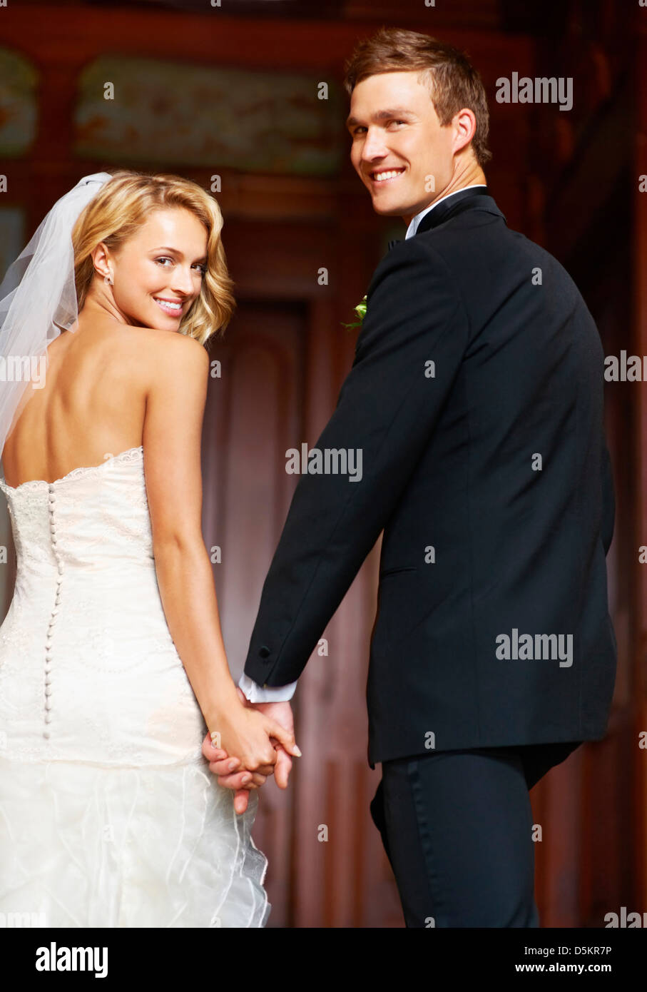 Young couple looking over shoulders towards camera Stock Photo - Alamy