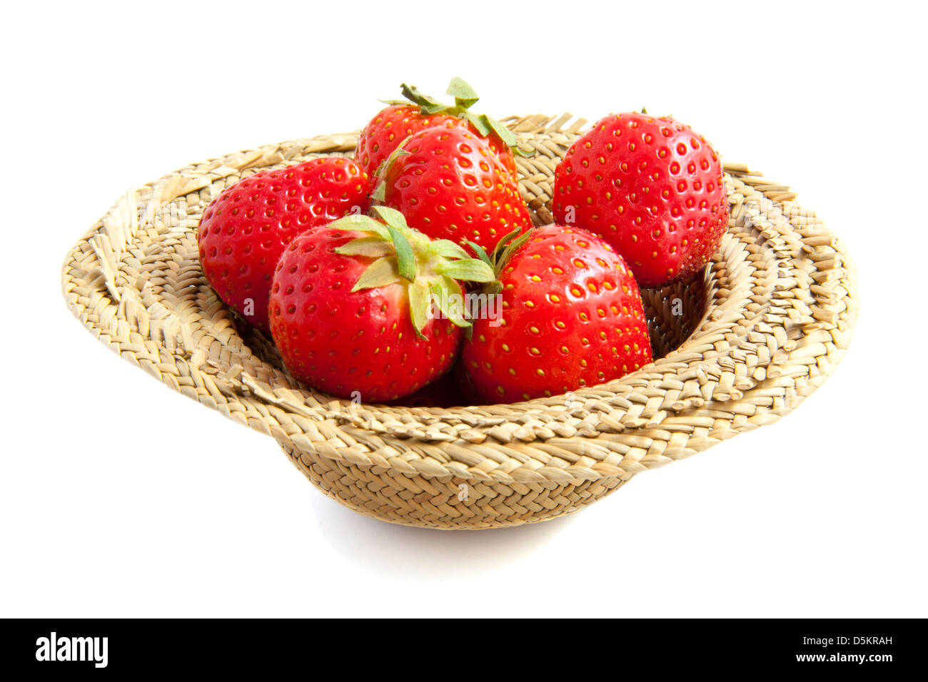 Straw hat filled with fresh strawberries isolated over white Stock ...