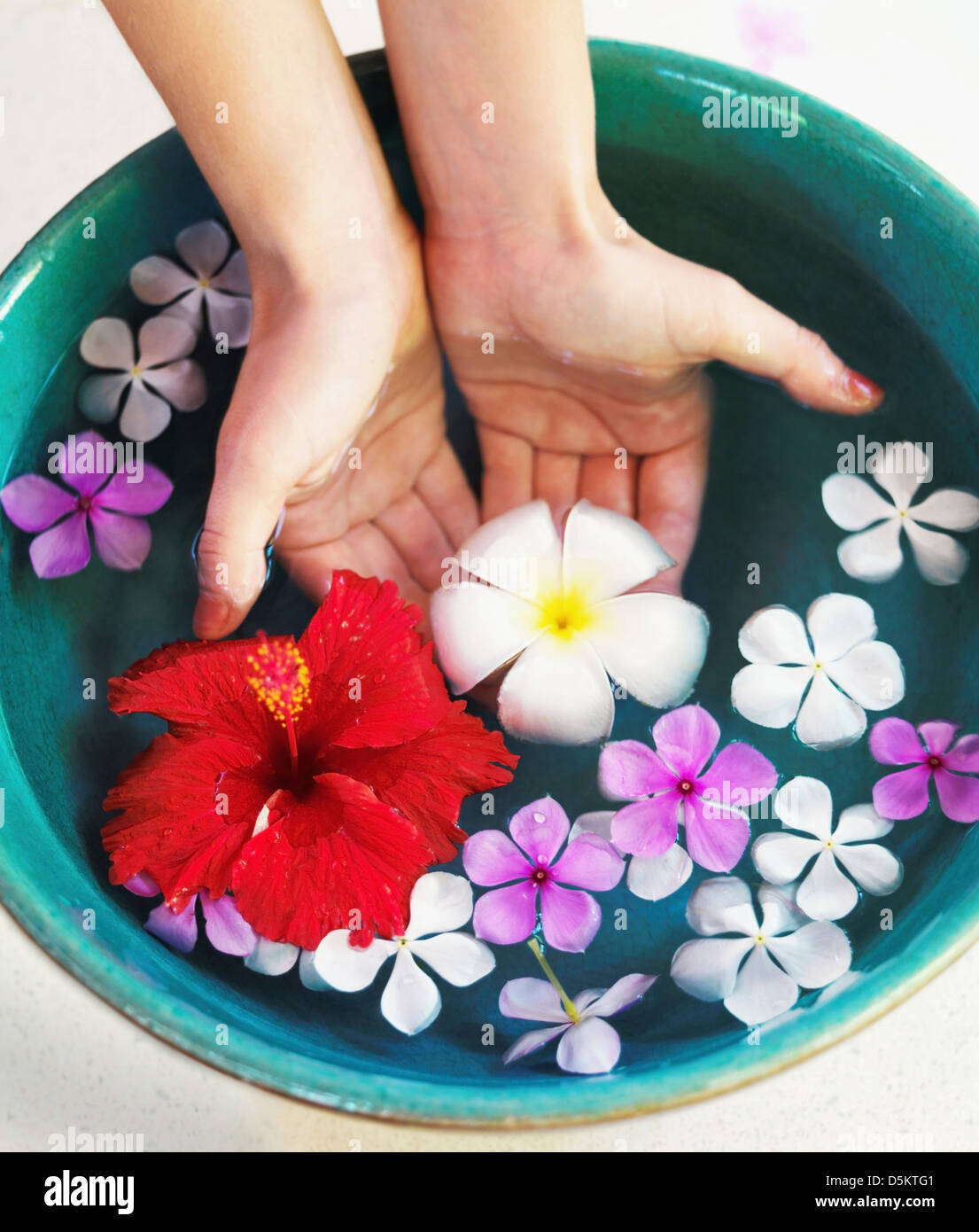 Human hands in bowl with floating flower heads Stock Photo - Alamy