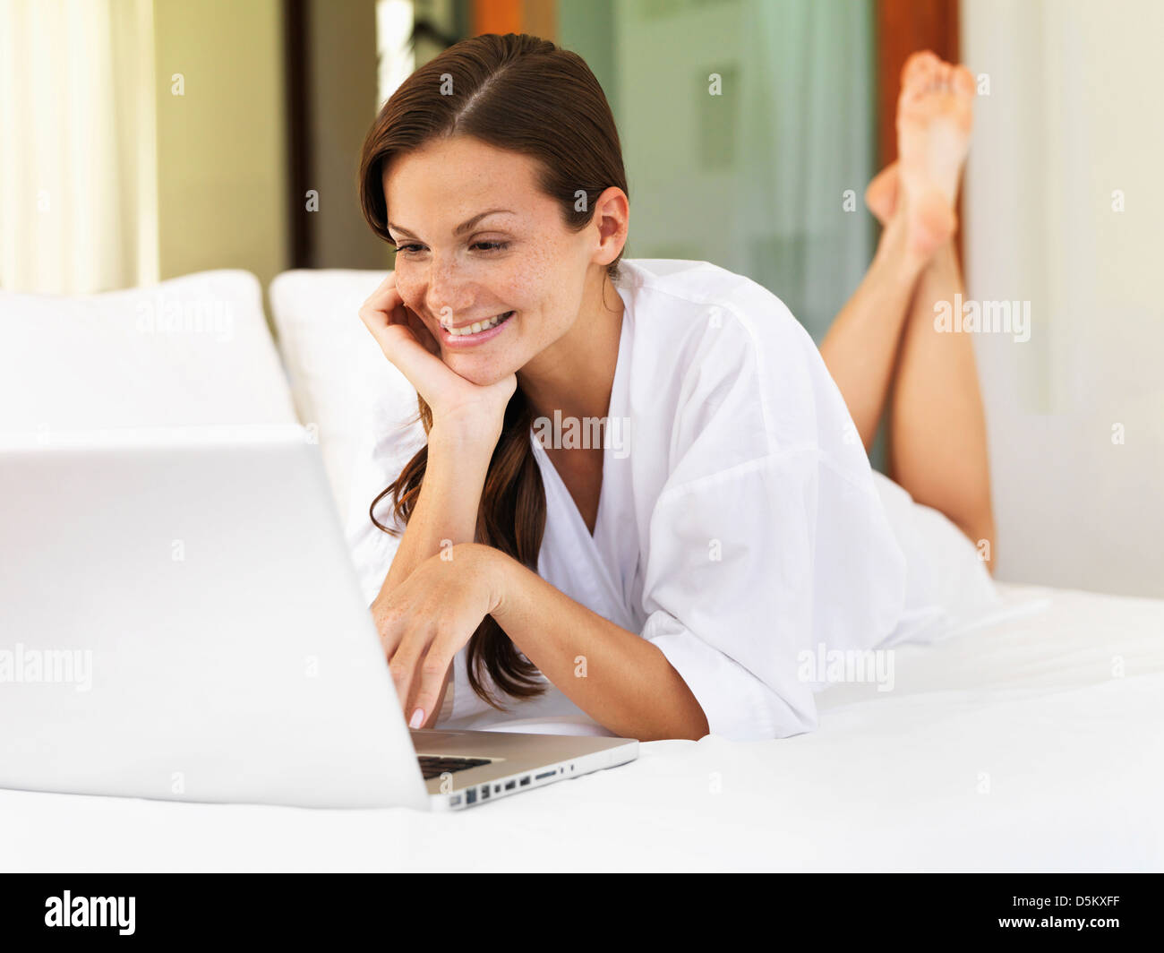 Woman using laptop while lying on bed Stock Photo - Alamy