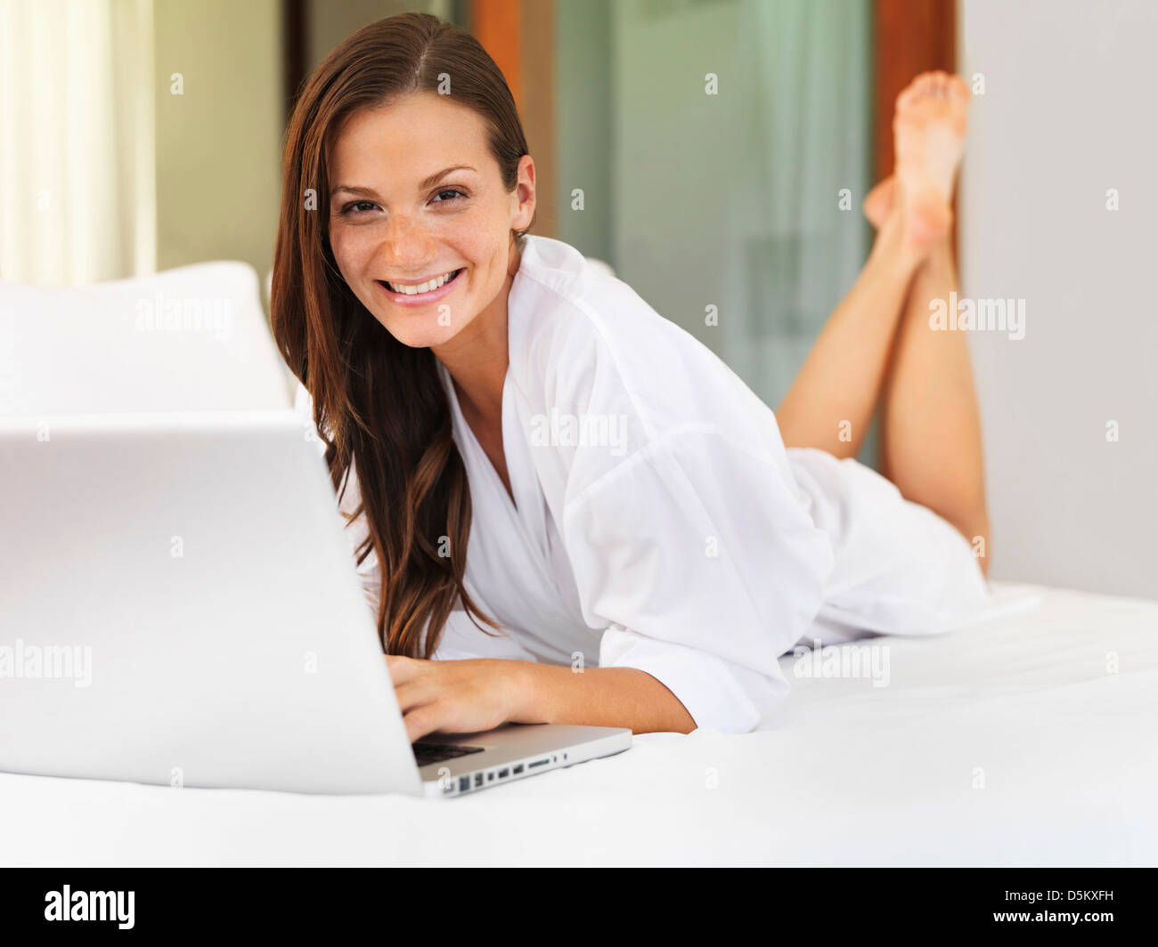 Woman using laptop while lying on bed Stock Photo - Alamy