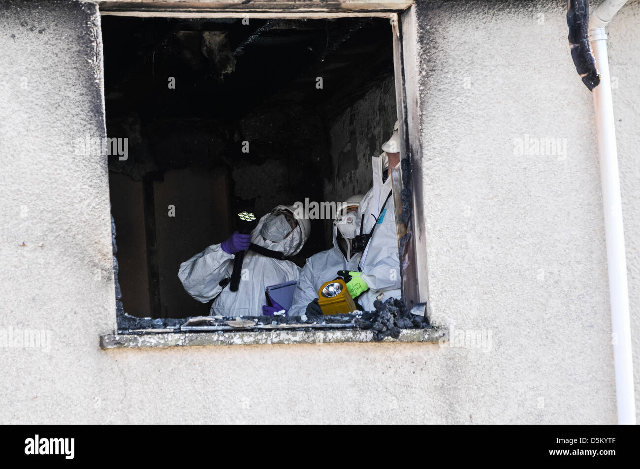 Fire investigation officers examine the scene of a fatal house fire to ...