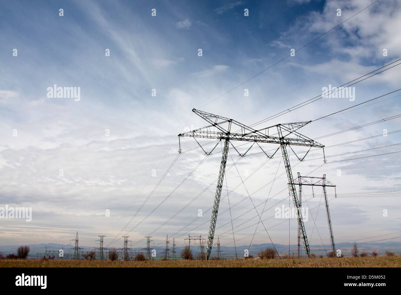 Steel lattice high voltage transmission towers in a field, blue sky ...