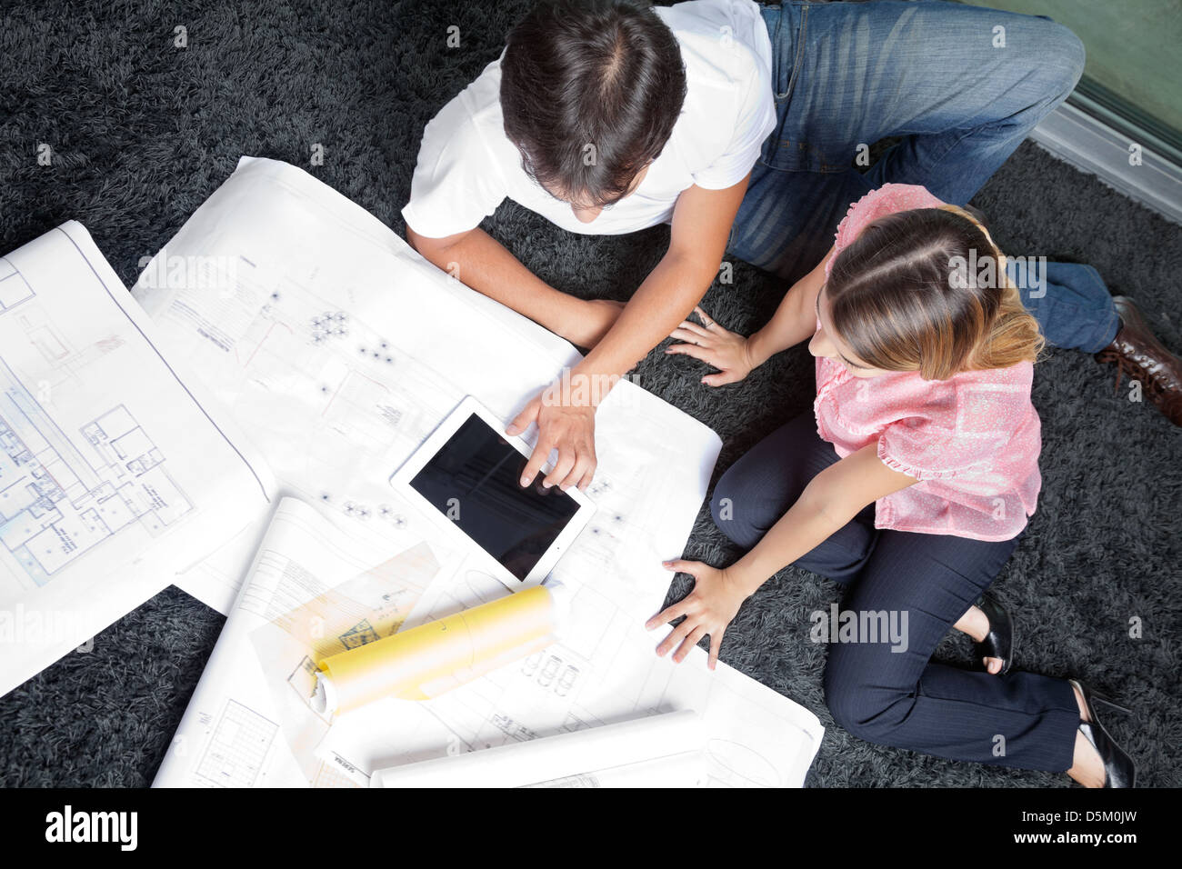 Couple Sitting On Rug With House Plans Stock Photo - Alamy
