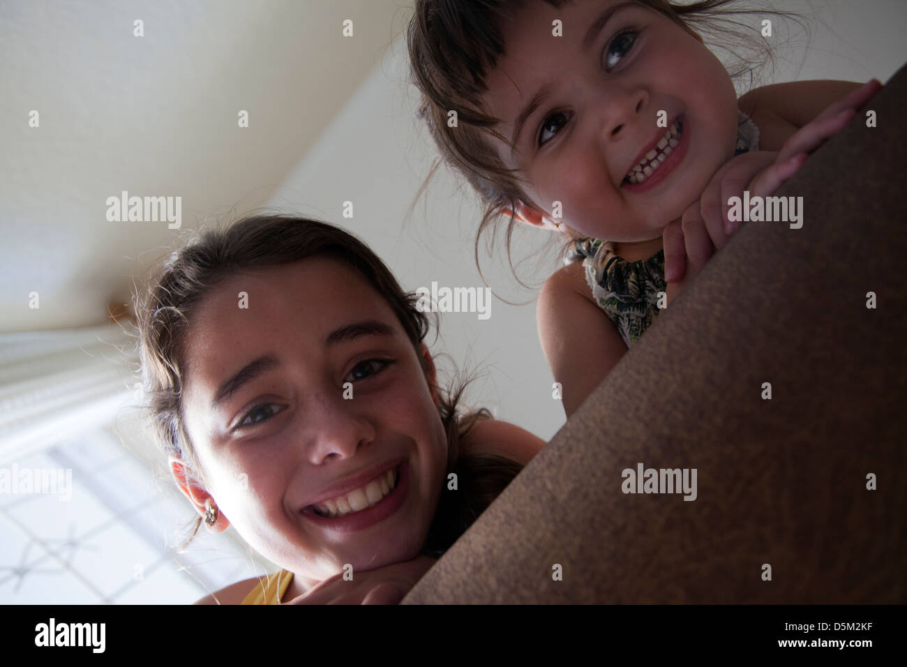 Two Girls (Cousins) leaning over Couch and Smiling Stock Photo - Alamy