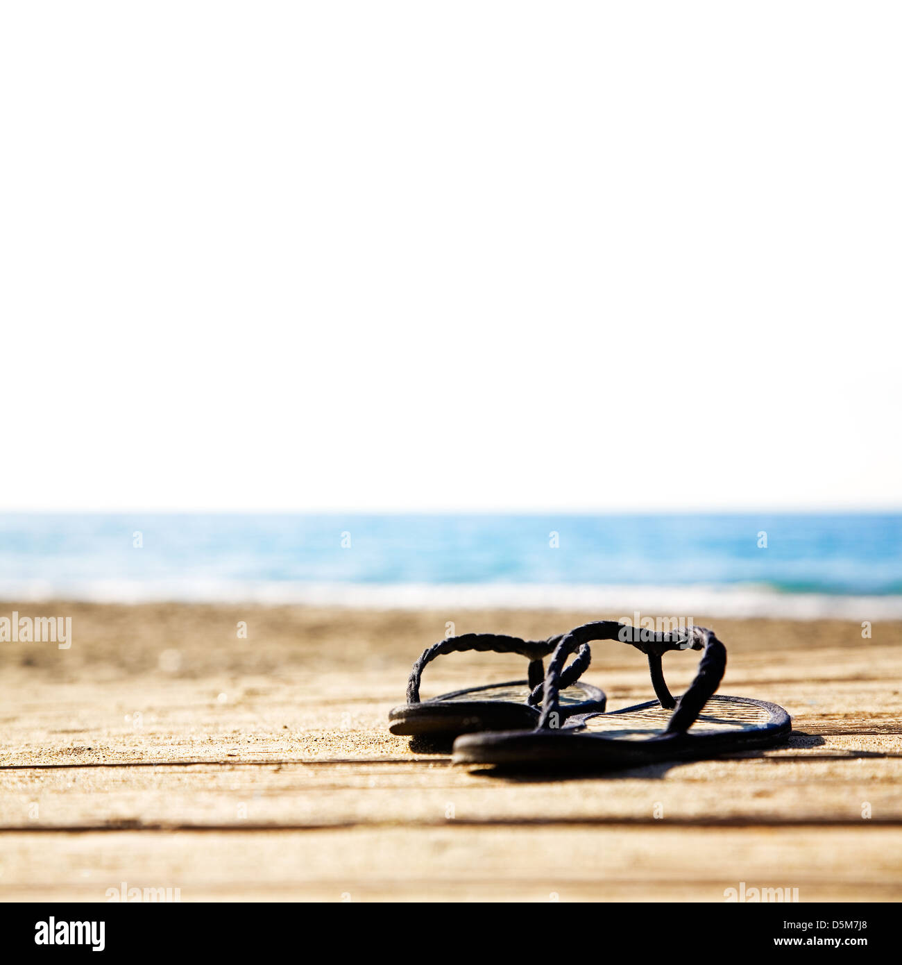 Black summer sandals on the sandy dock Stock Photo - Alamy