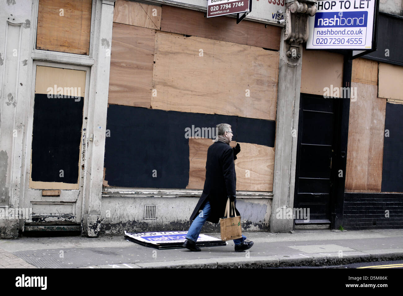 Man walking past boarded up shops in central London Stock Photo - Alamy