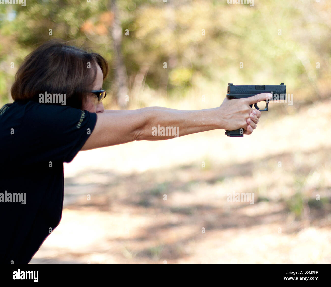 White woman aiming a pistol while standing in the isosceles position at ...