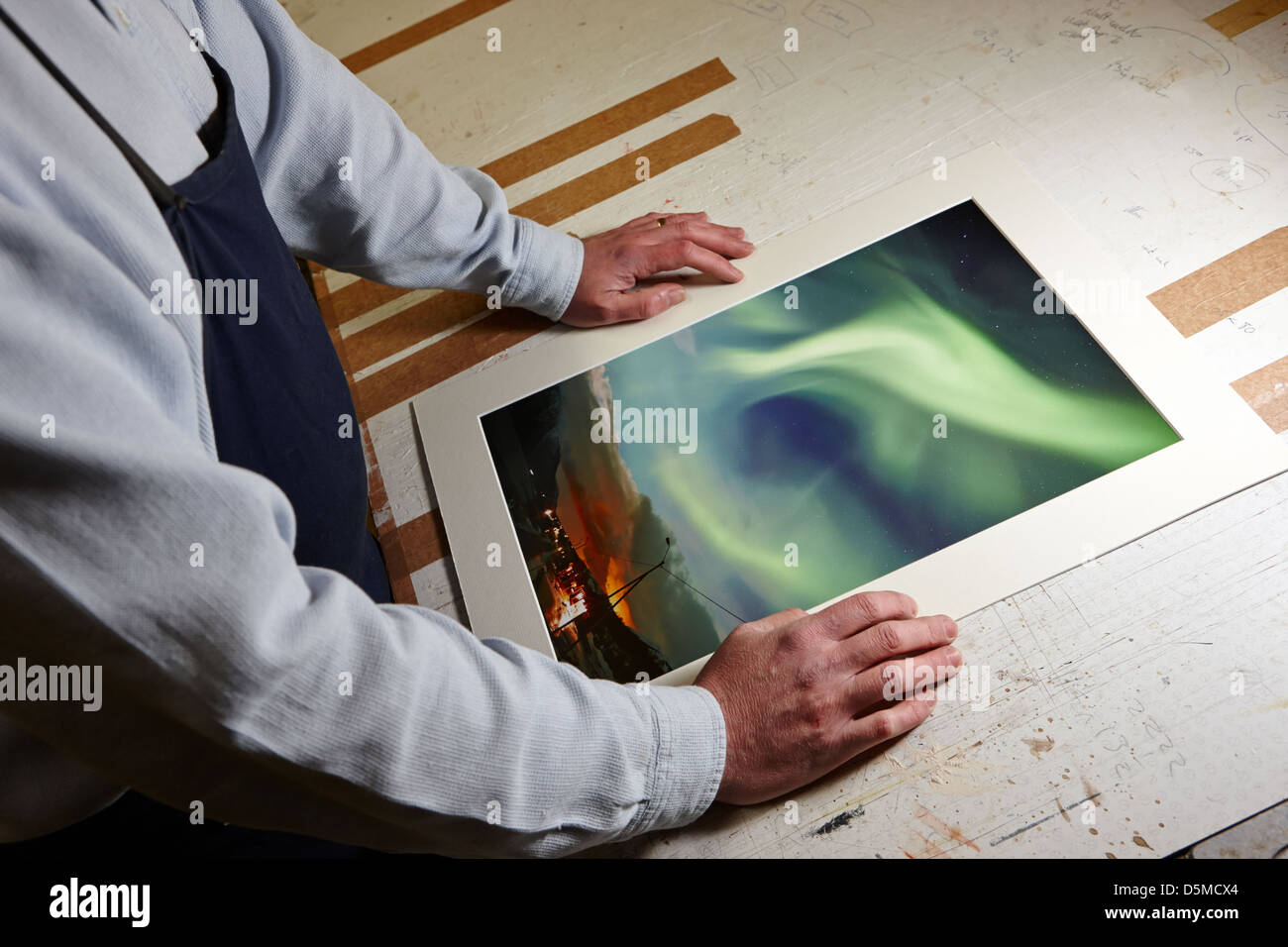 framer placing photograph in bespoke cut mount in a framing workshop ...