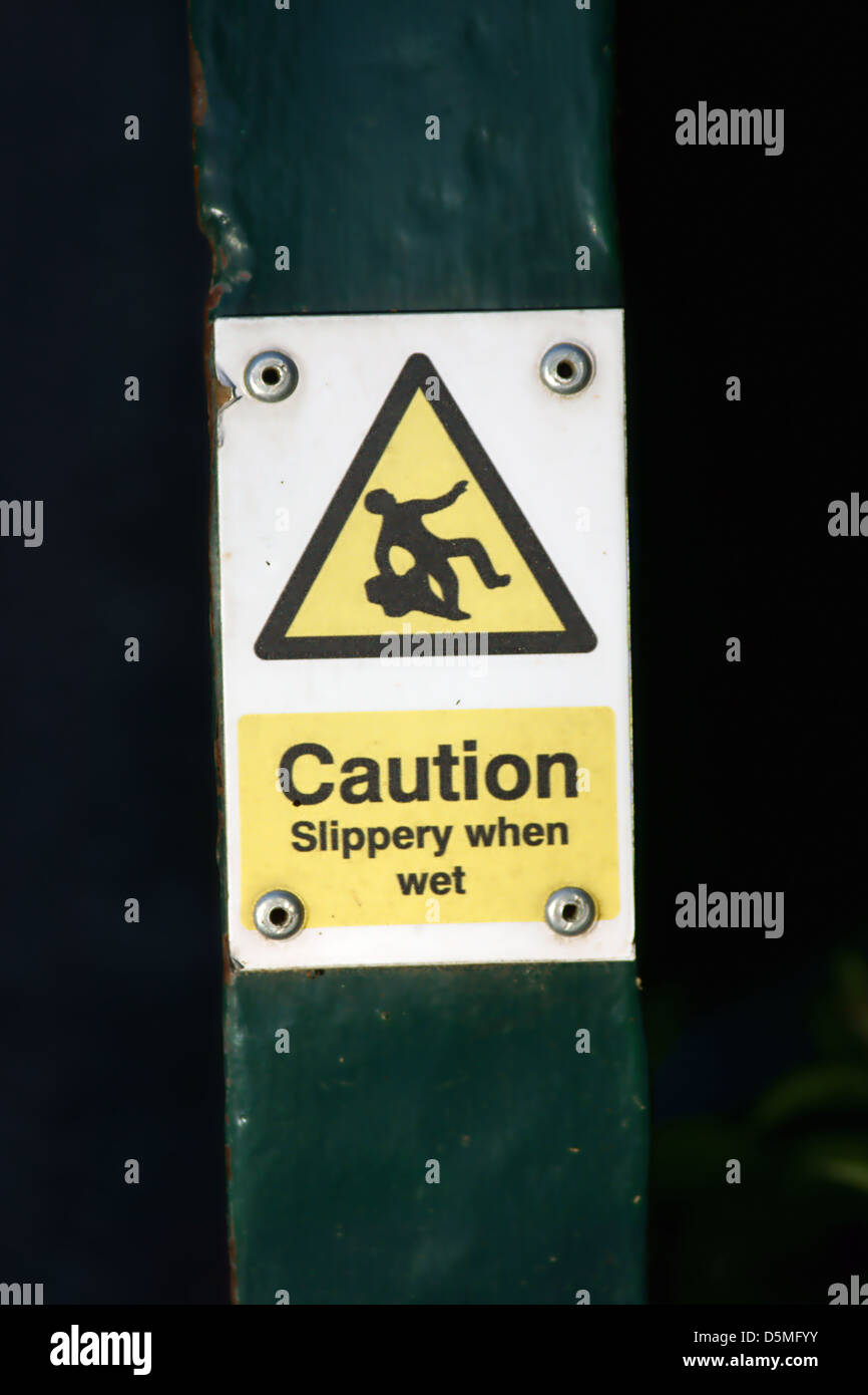 caution slippery when wet sign on green railing Stock Photo - Alamy