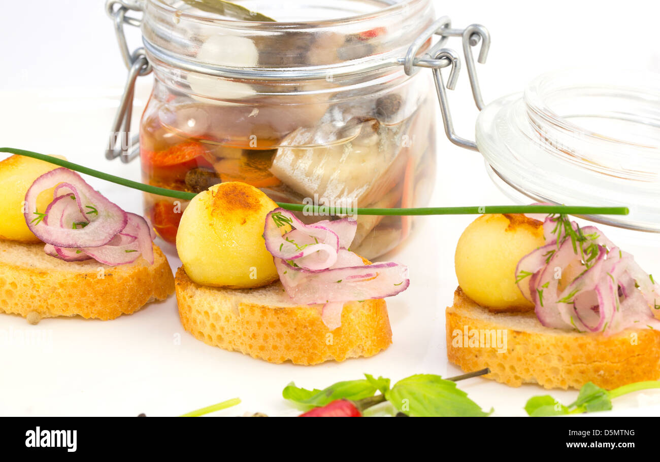 pickled herring in a glass jar with potato canapes Stock Photo - Alamy