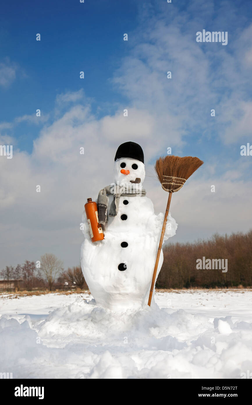 Decorated happy snowman with carrot nose, hat, pipe, scarf and broom in ...