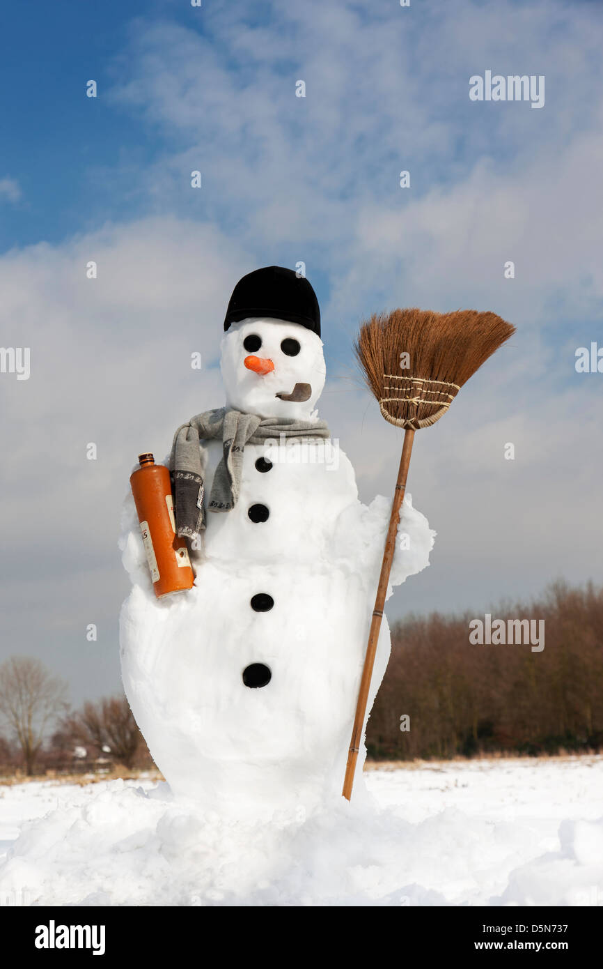 Decorated happy snowman with carrot nose, hat, pipe, scarf and broom in ...