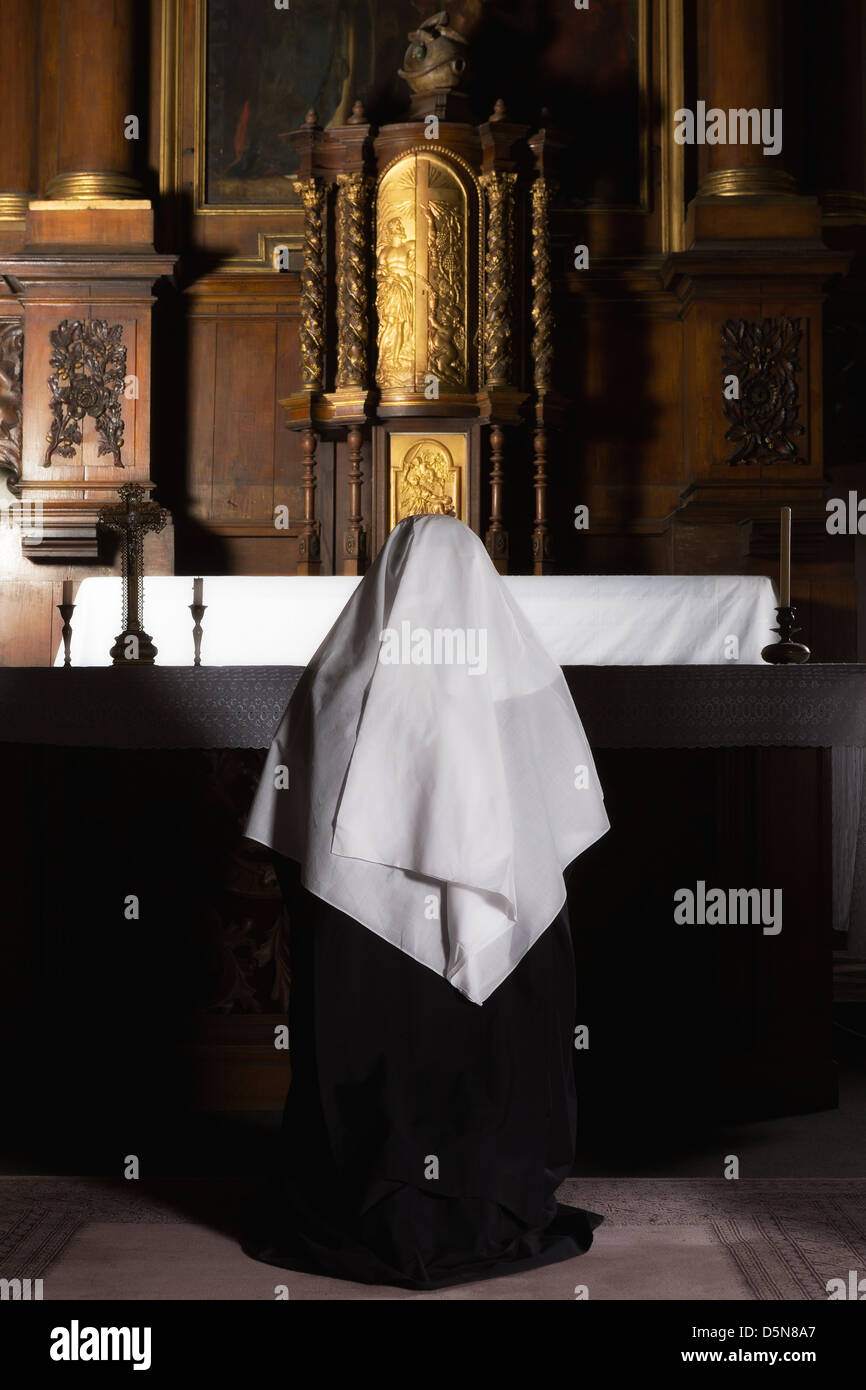 Nun praying at the altar of a medieval 17th century church with ...