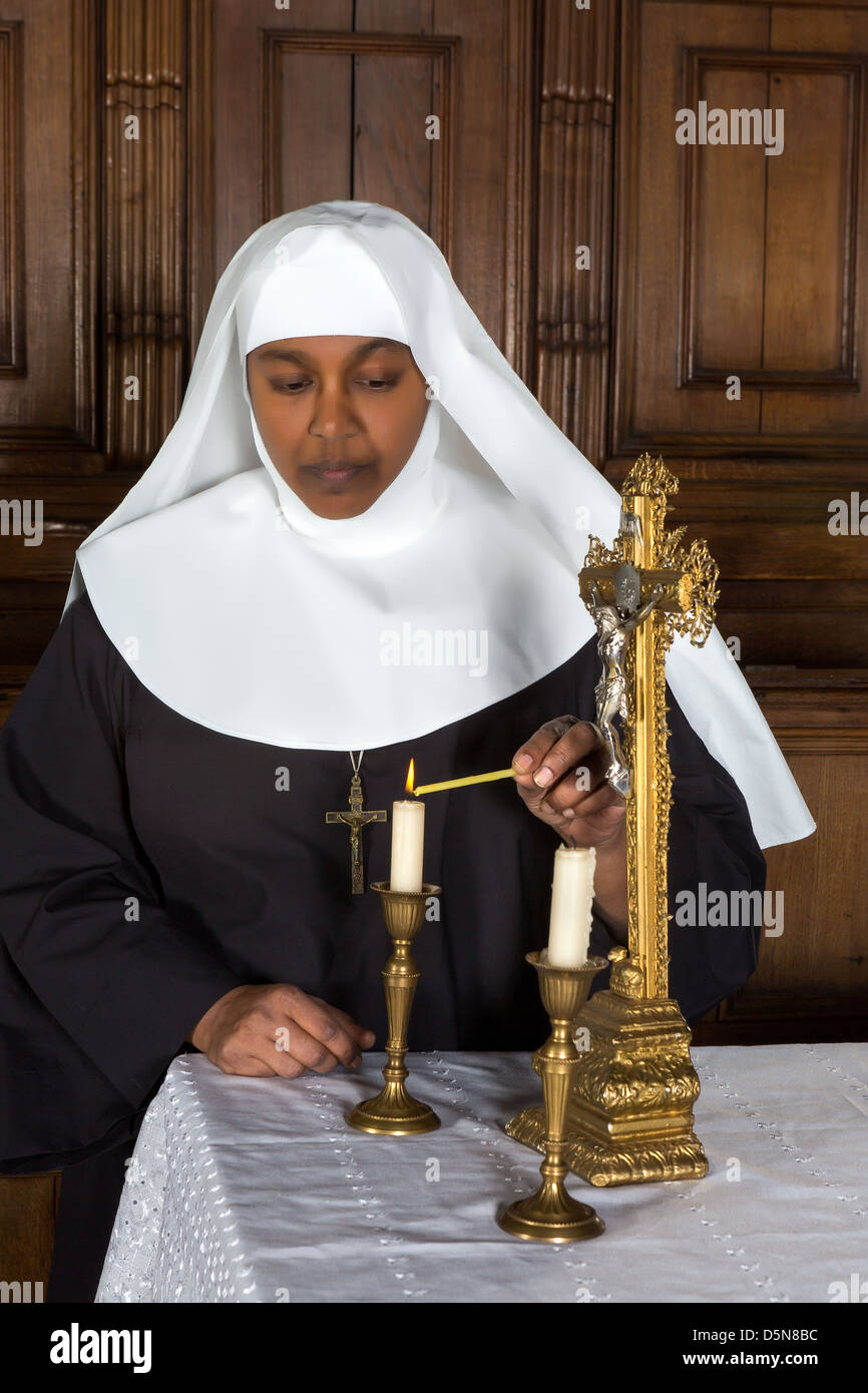 Nun standing at the altar and lighting a candle Stock Photo - Alamy