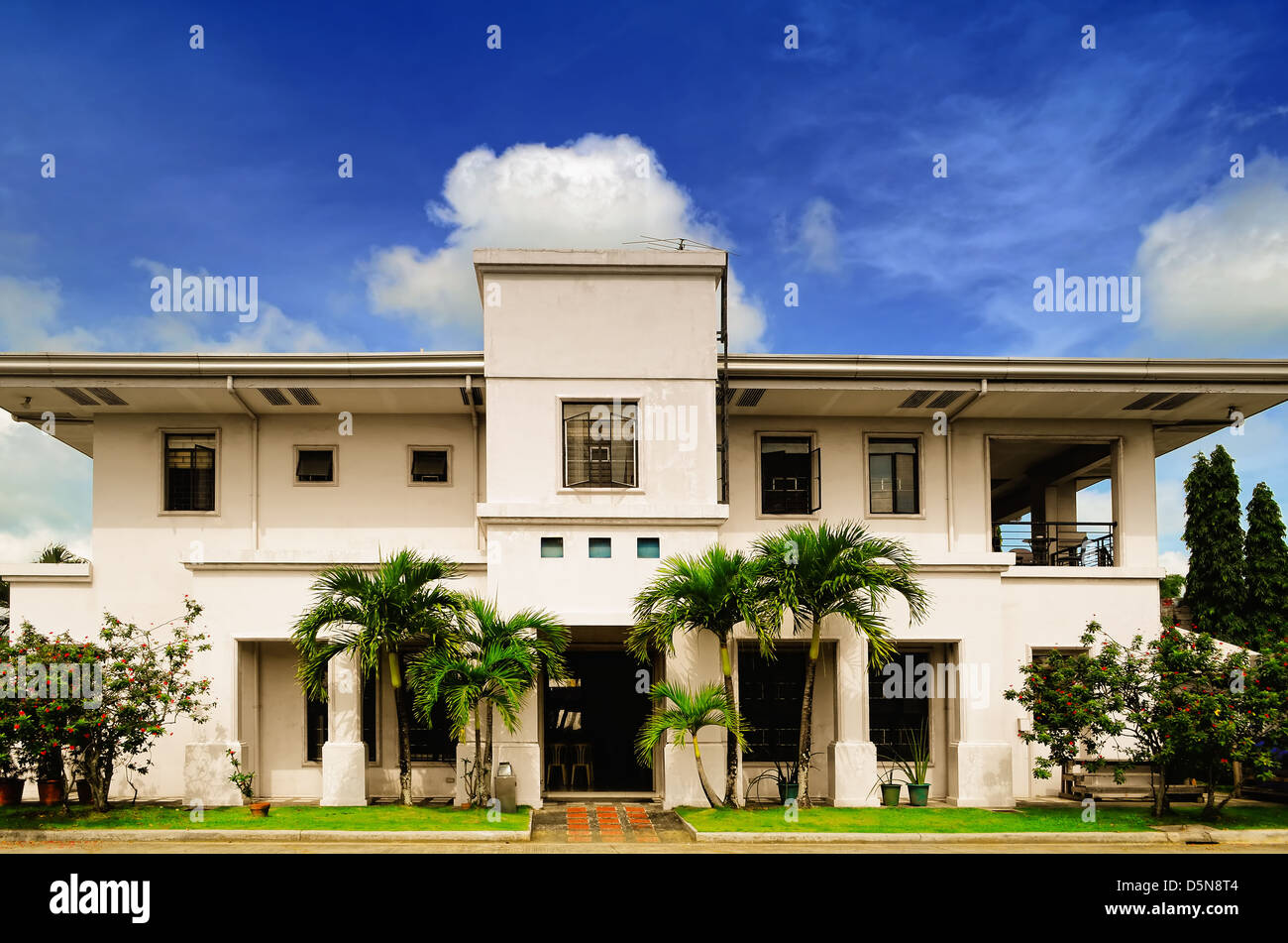 Two-Floor white building with plants in front; shot against blue sky ...