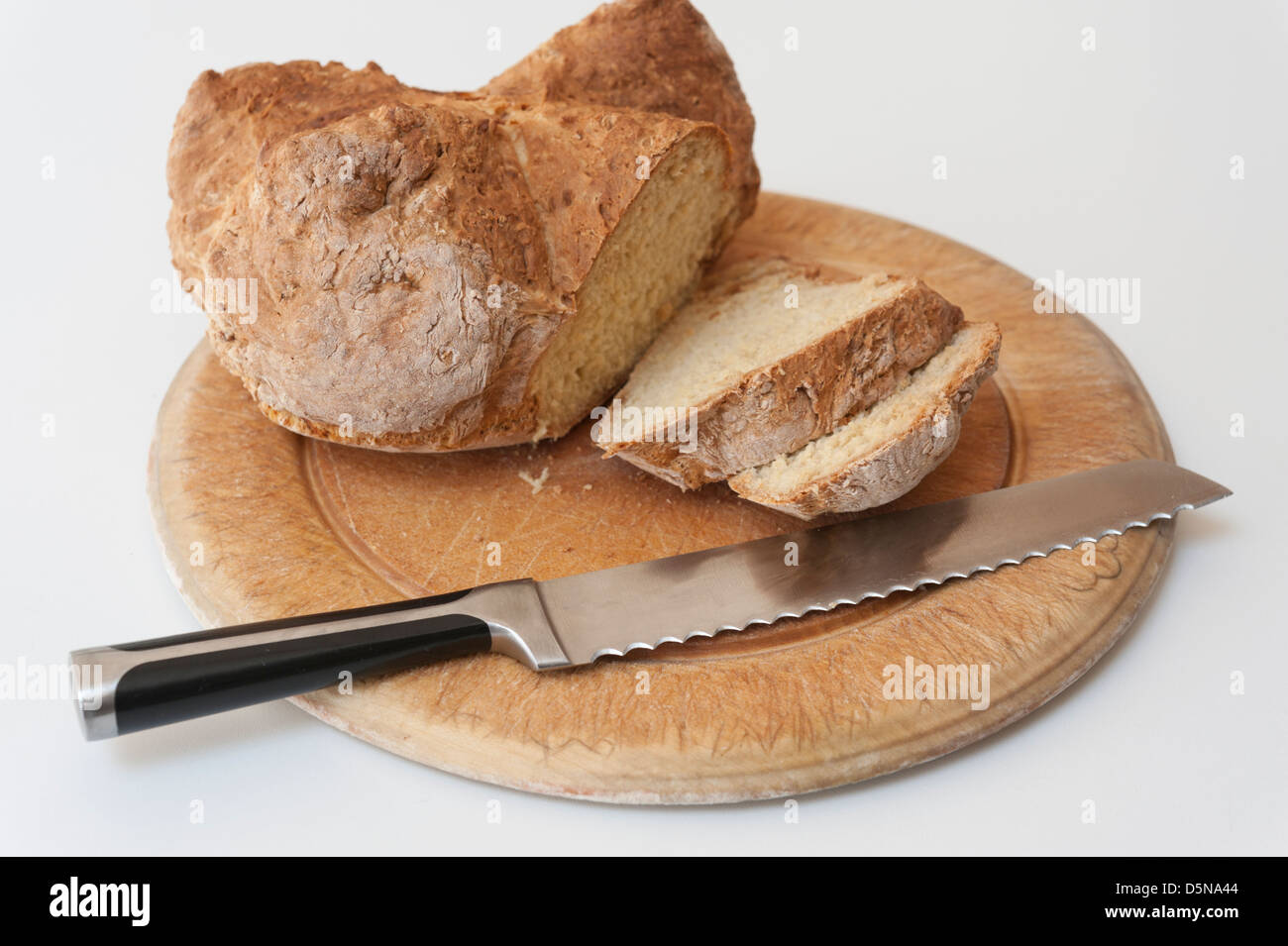 A freshly baked homemade loaf of soda bread on a bread board with bread ...