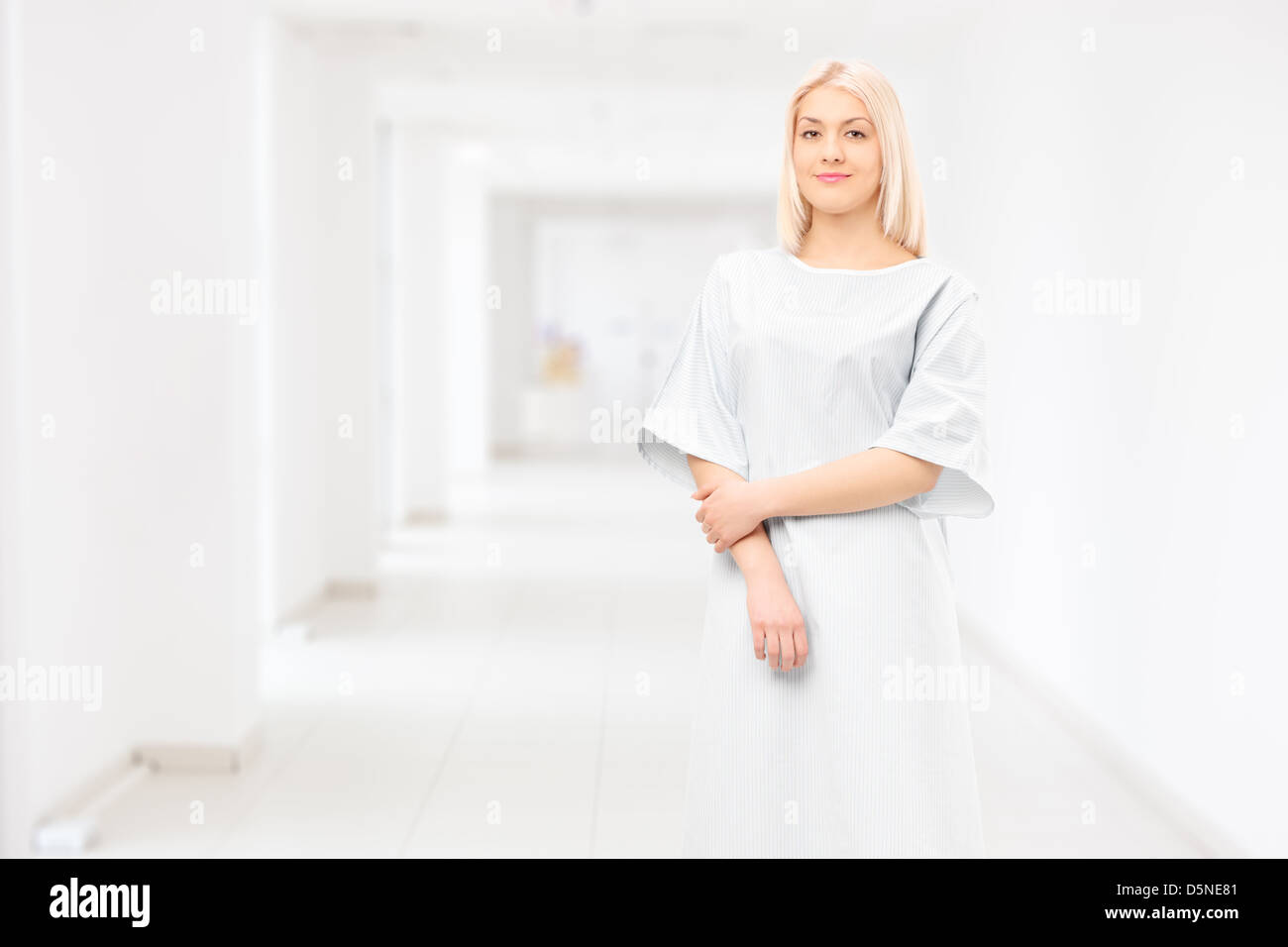 Female patient wearing hospital gown and posing in a hospital corridor ...