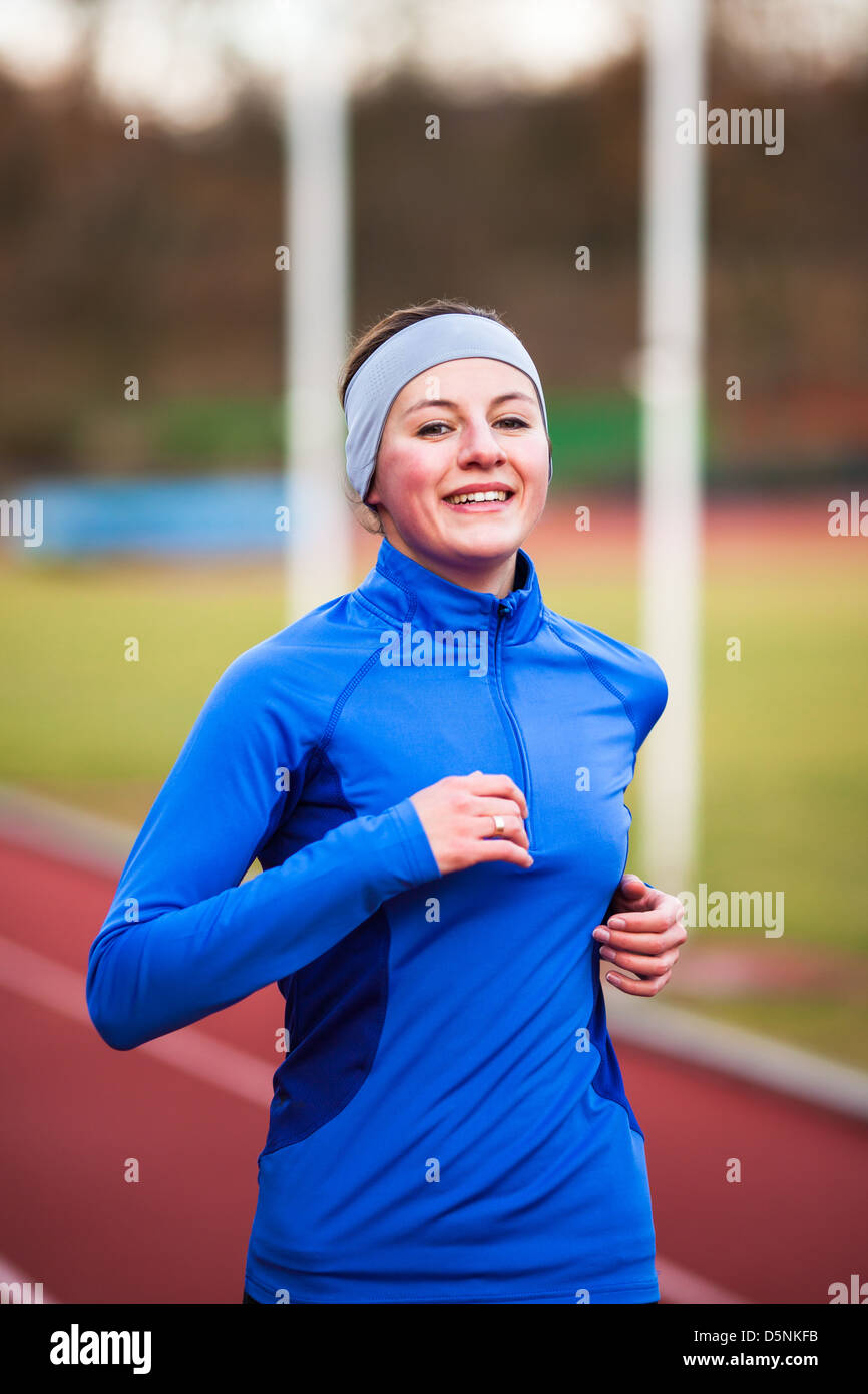 Young woman running at a track and field stadium Stock Photo - Alamy