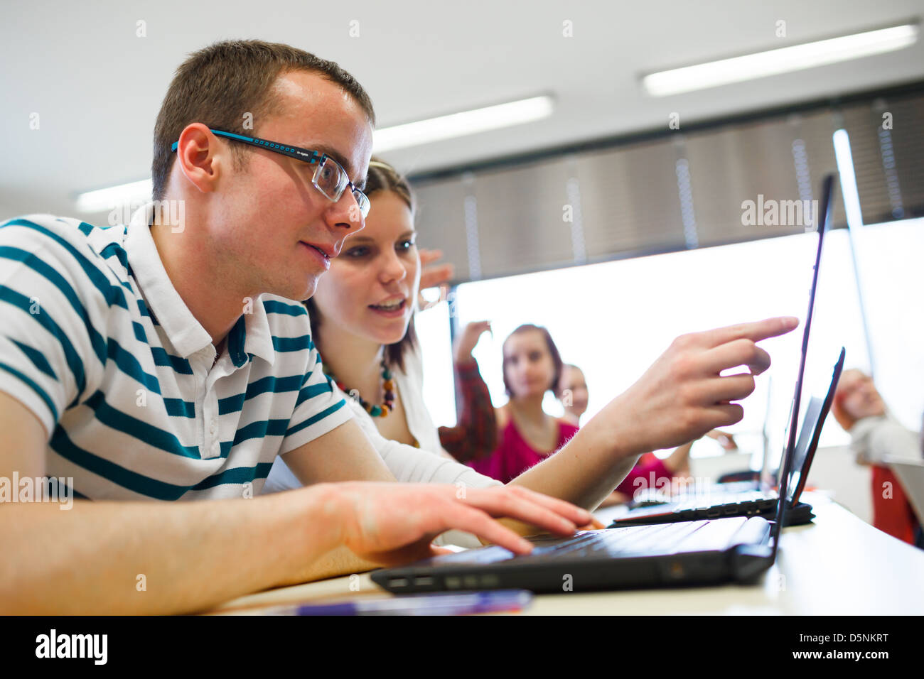 College students sitting in a classroom, using laptop computers during ...