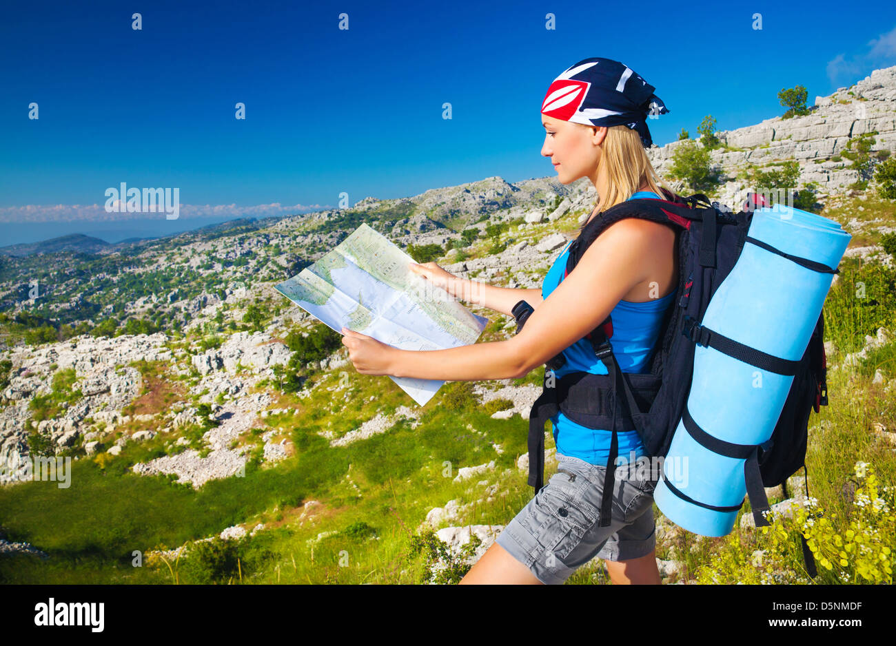 Cute blond girl in the mountains looking way on the map, summer ...