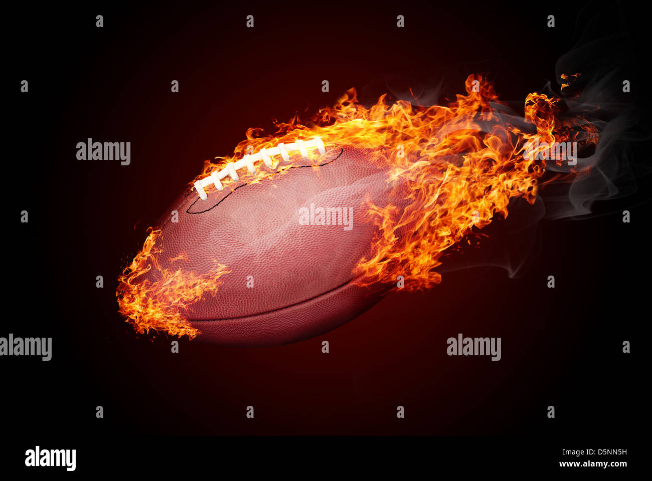 American football ball in fire isolated on dark red background - flying ...