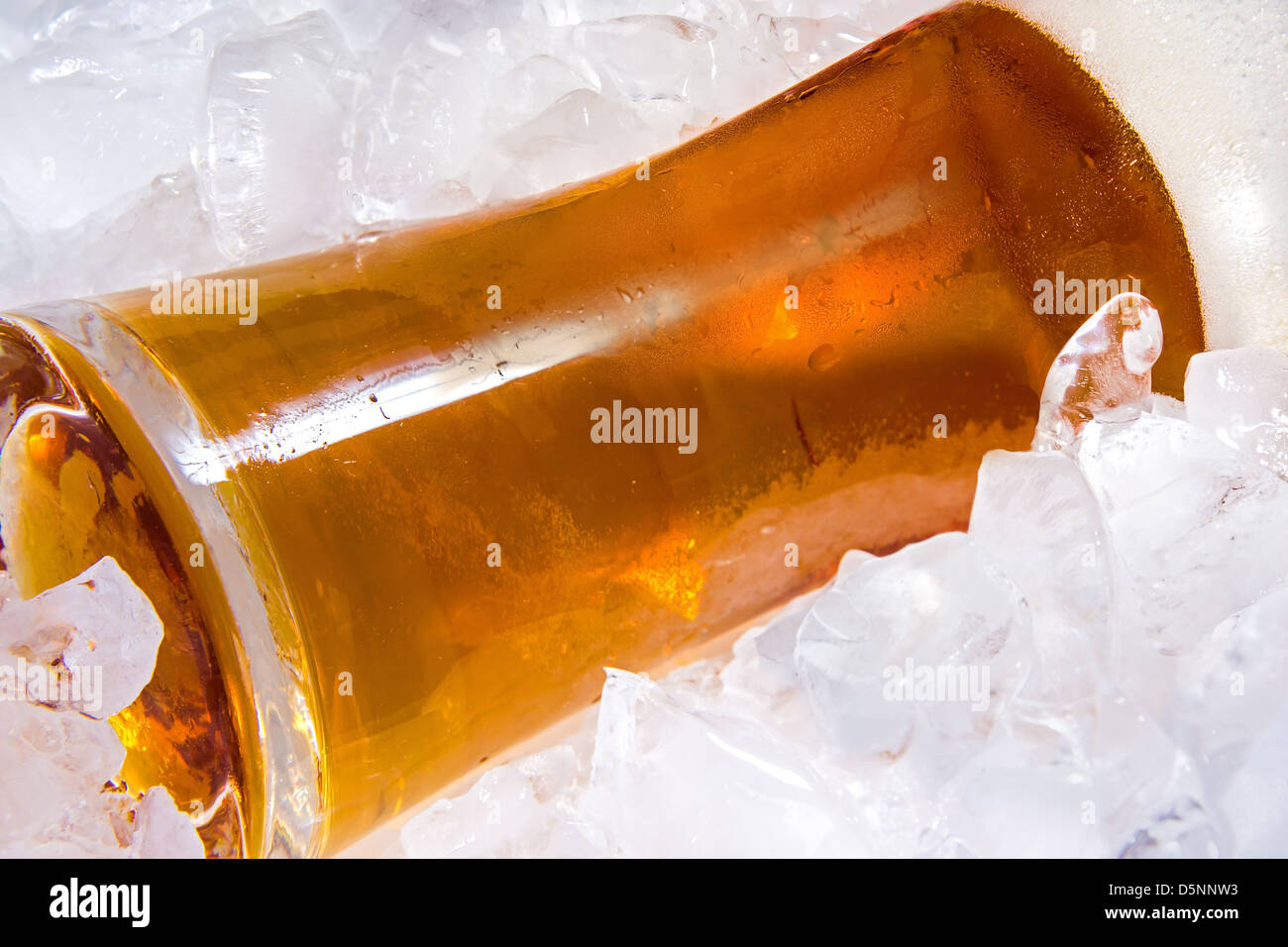 Glass of cold beer lying in the ice Stock Photo - Alamy