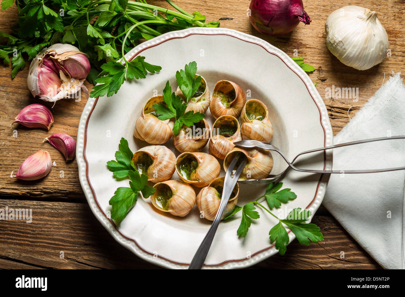 Snails baked in garlic butter and served with parsley Stock Photo - Alamy