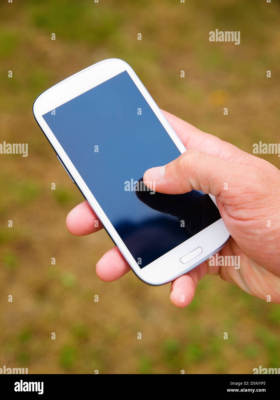 Man hand touching screen on modern mobile smart phone on natural green ...