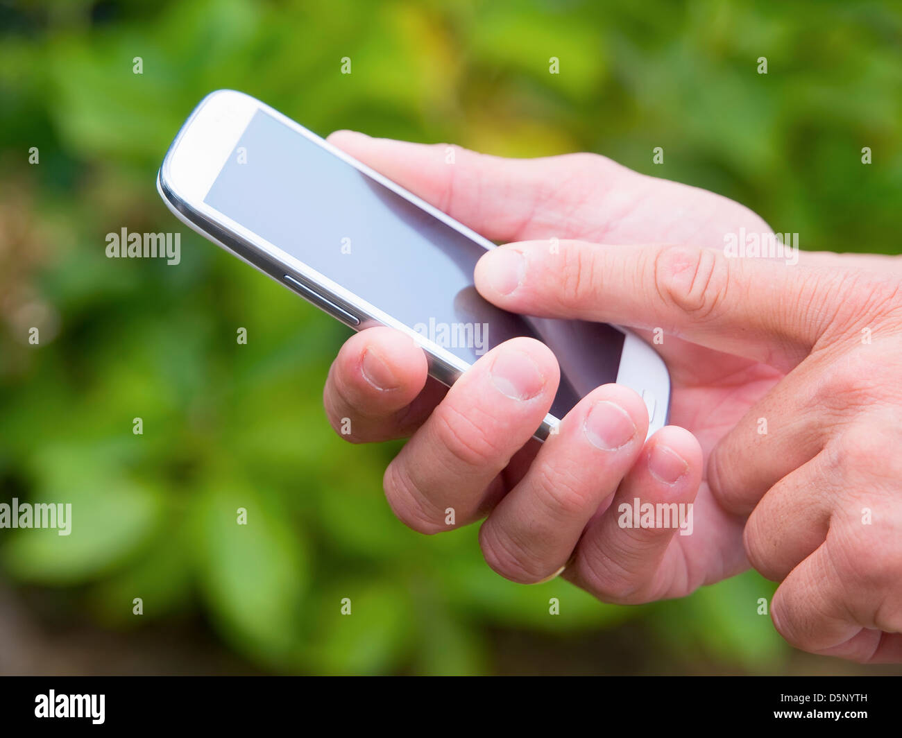 Man hand touching screen on modern mobile smart phone on natural green ...