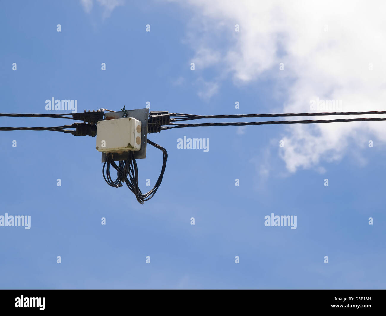 electrical transformer on a cable and sky background with a white cloud ...